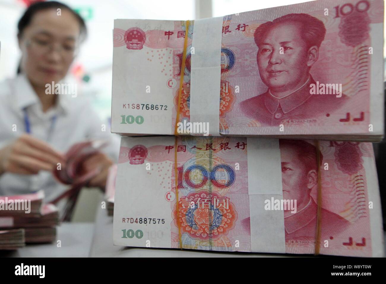 Eine chinesische Angestellte zählt RMB (Renminbi) Yuan Banknoten bei ...