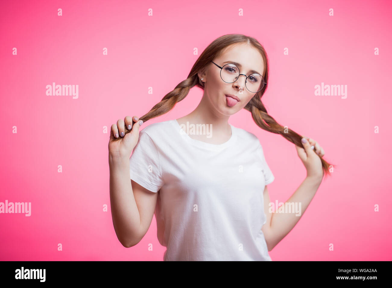 Lustige nette junge Mädchen mit Zopf und Gläser, die Zunge an der ...