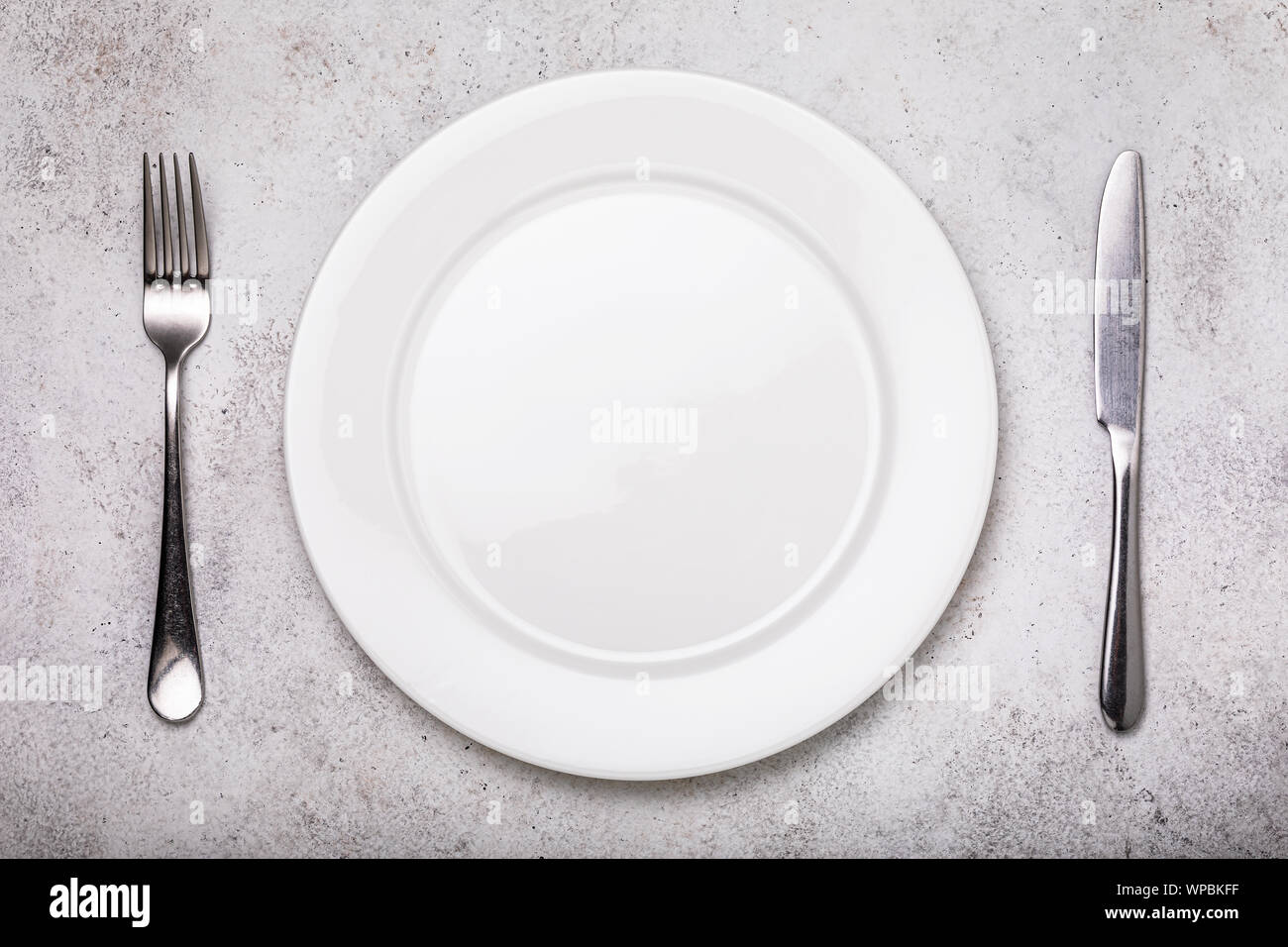 Leer weißer Keramik Teller und Besteck auf dem Tisch, Ansicht von oben ...