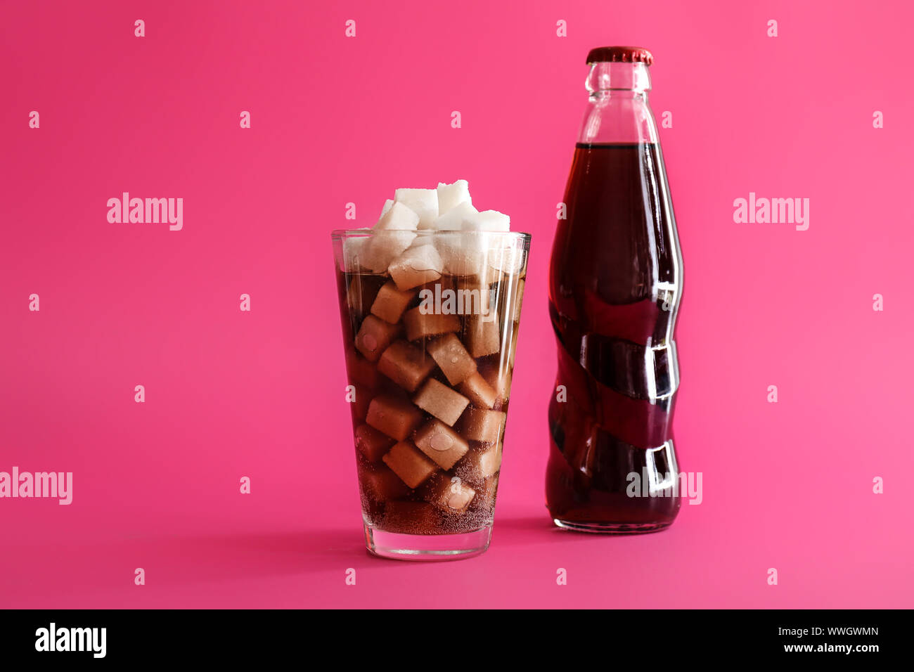 Flasche und Glas Cola mit Zucker Würfel auf farbigen Hintergrund ...