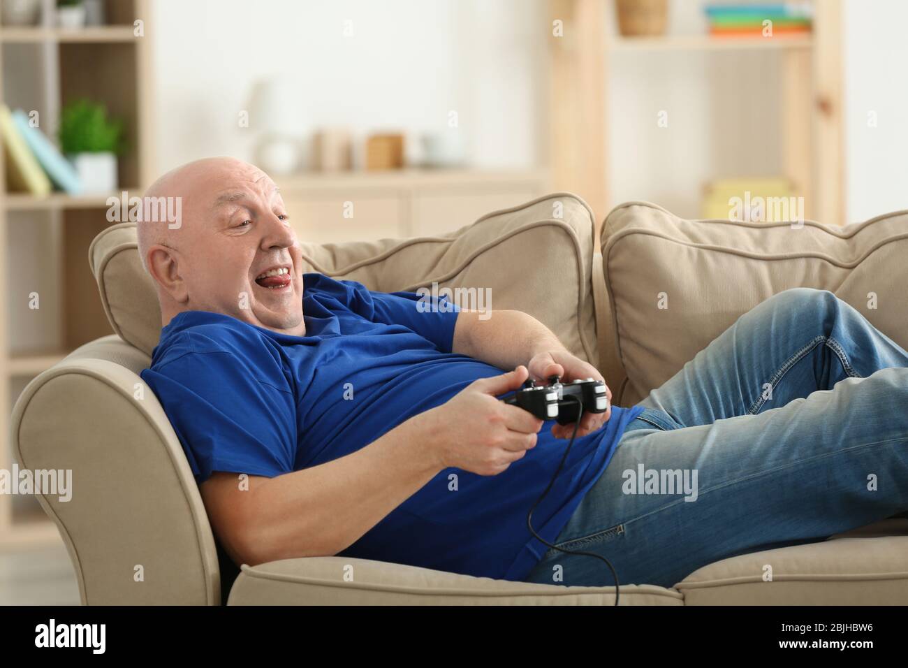 Gordo hombre mayor jugando videojuego mientras se acostaba en el sofá ... Gordo hombre mayor jugando videojuego mientras se acostaba en el sofá ...