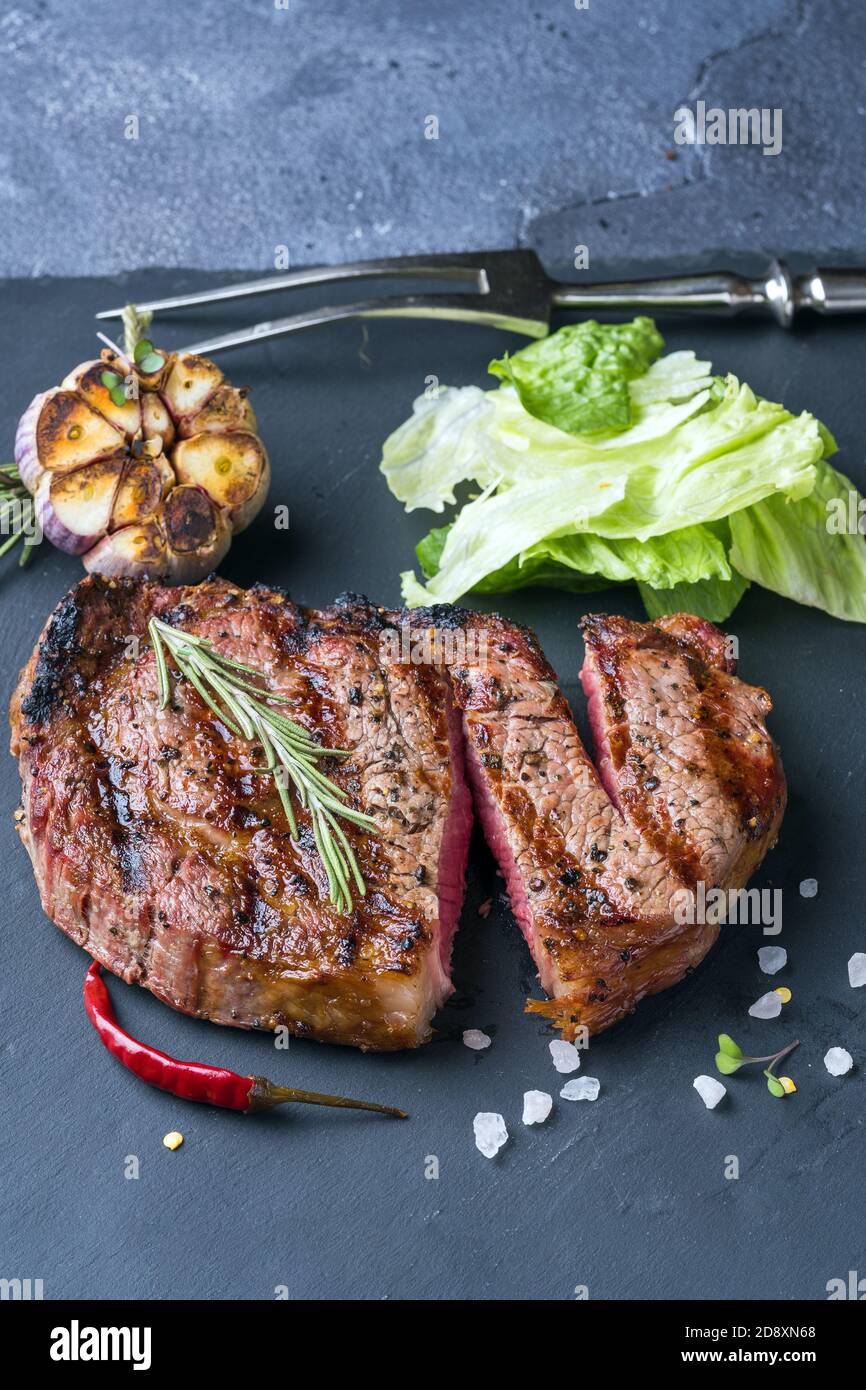 Un filete de ribeye recortado con ramita de romero en un losa de piedra ...