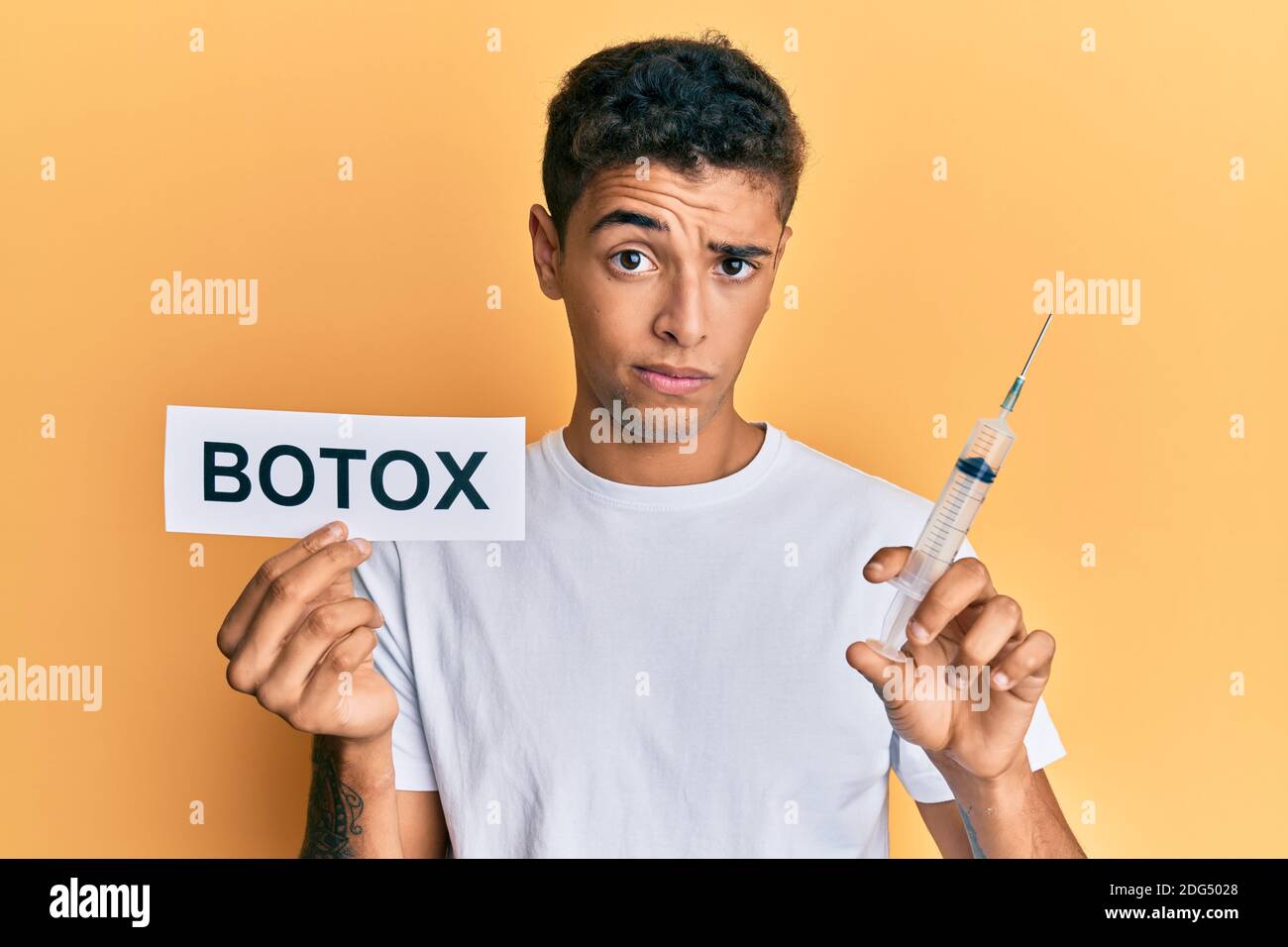 Joven Hombre Afro Americano Con Pancarta De Botox Y Aguja Escéptico Y