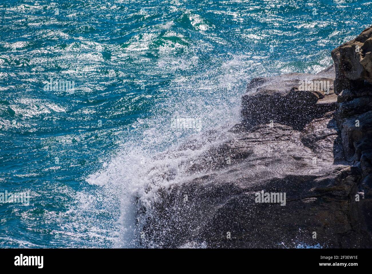 El agua de mar late contra las rocas. Olas de agua oscura golpean ...