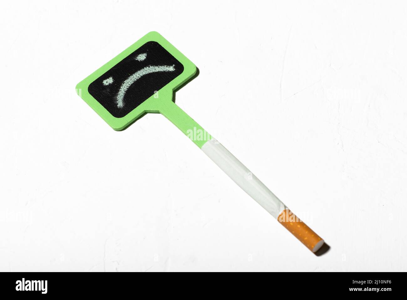 Concepto de daño al fumar. Emoticono y cenicero infeliz con colillas de ... Concepto de daño al fumar. Emoticono y cenicero infeliz con colillas de ...