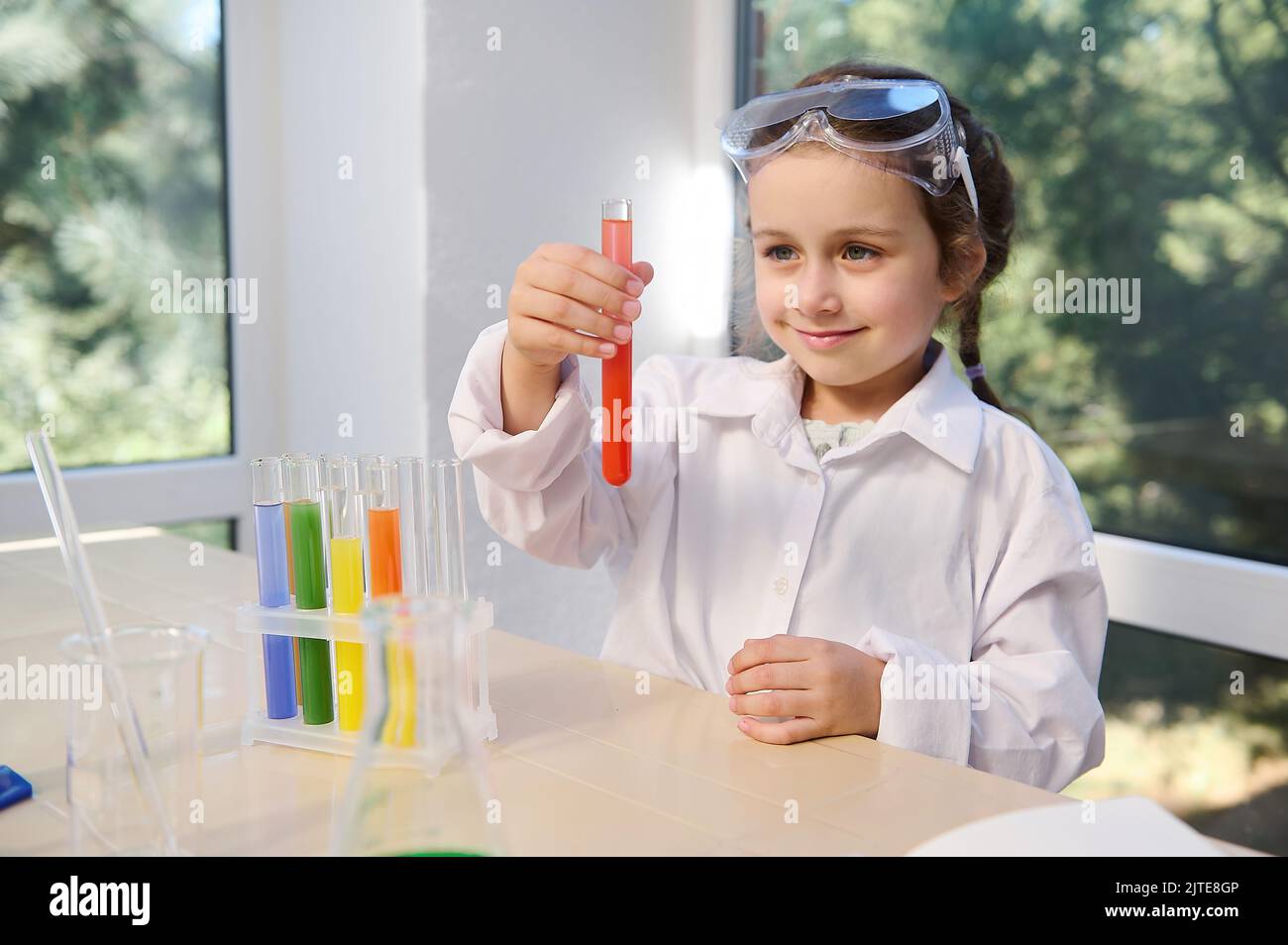 Niño bonito con gafas de seguridad y bata de laboratorio haciendo ...