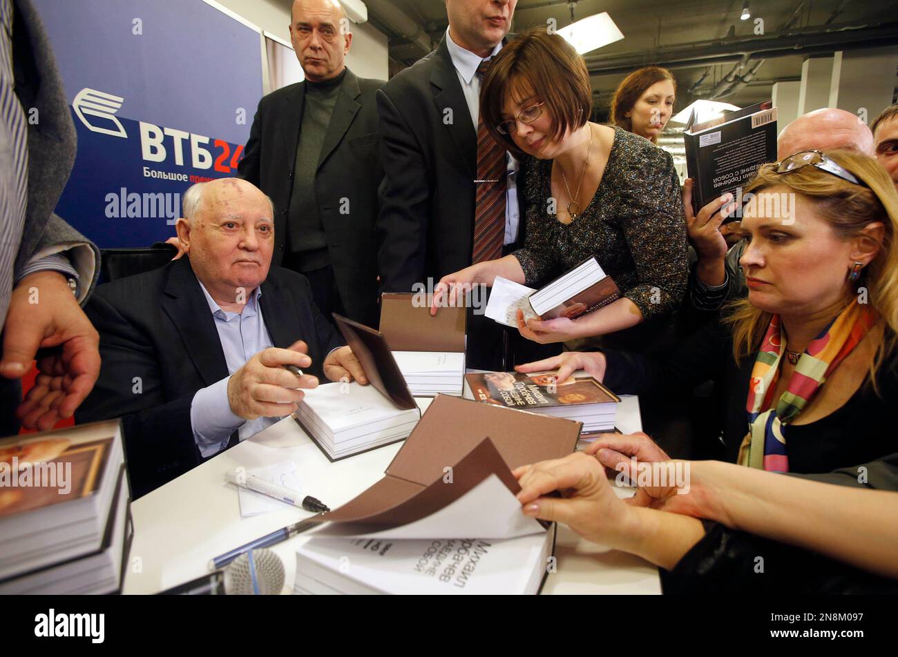 Former Soviet leader Mikhail Gorbachev, left, signs his book in a book ...