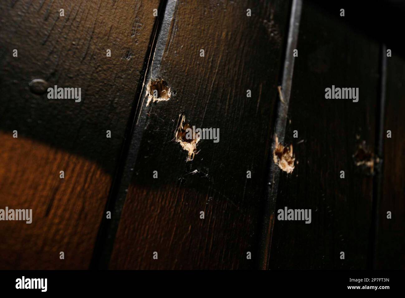 Four Bullet Holes Are Visible In The Wood Panel Behind The Chair In The