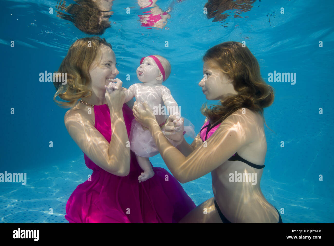 Mamá Y Dos Hijas En Vestido Rosado Posando Bajo El Agua En La Piscina