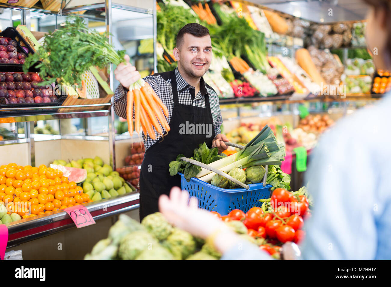 Asistente de compras masculino ayudando al cliente a comprar frutas y ... Asistente de compras masculino ayudando al cliente a comprar frutas y ...