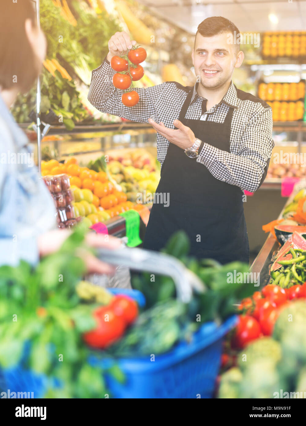 Asistente de compras masculino ayudando al cliente a comprar frutas y ... Asistente de compras masculino ayudando al cliente a comprar frutas y ...