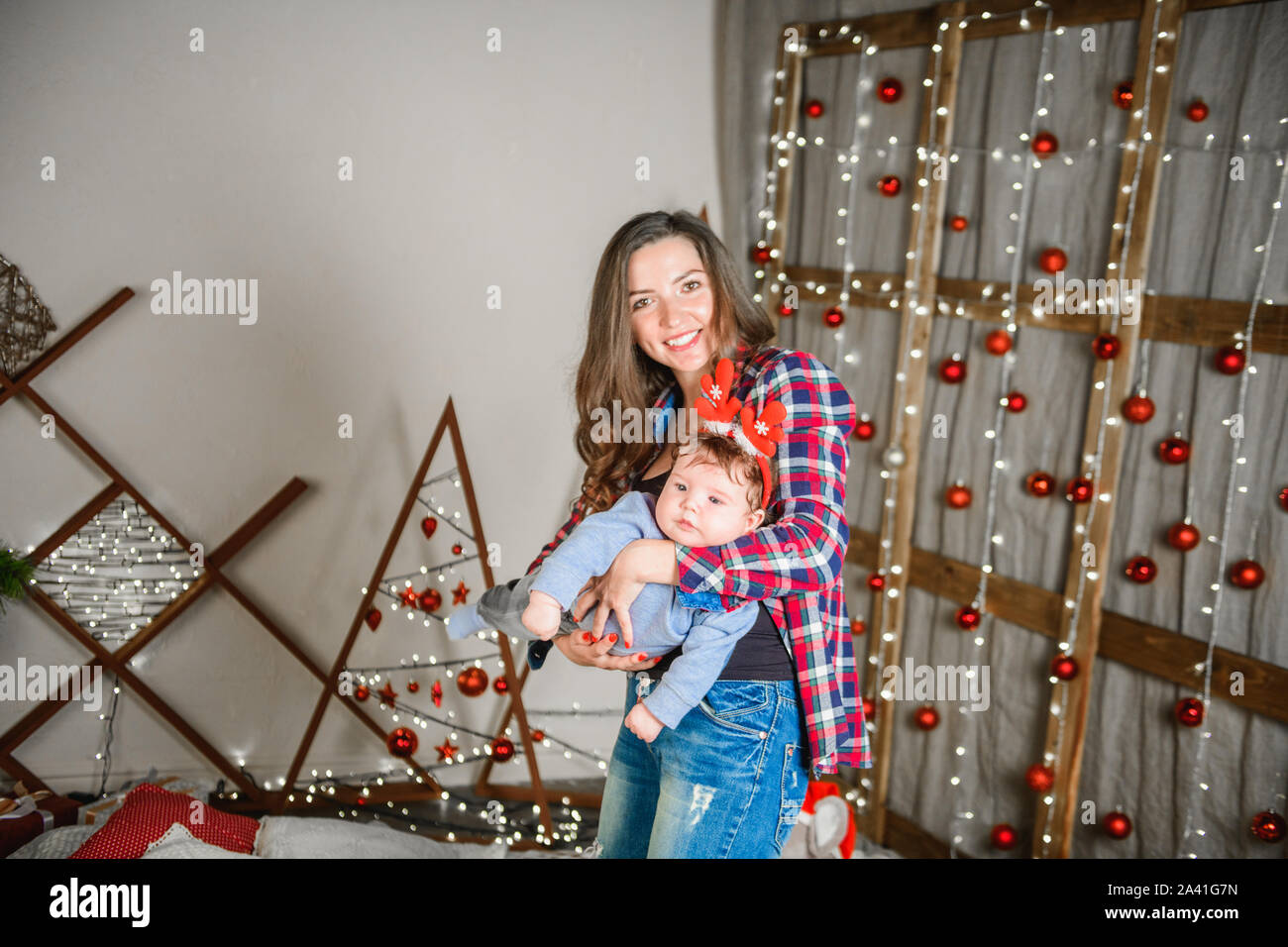 Maman et bébé câlin à l'arbre de Noël. Happy Baby et sa maman sont à la ...