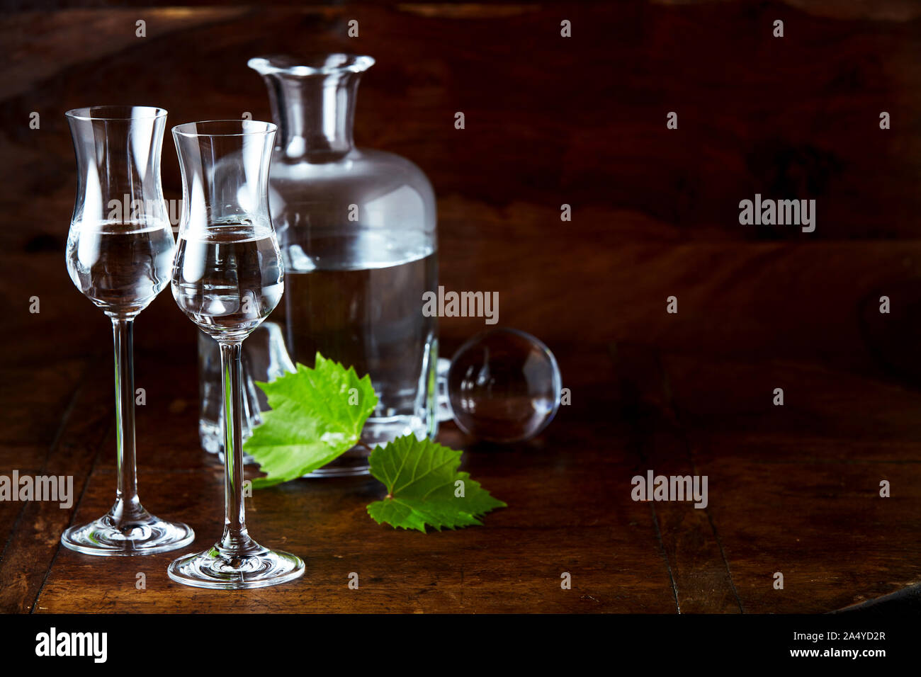Grappa Nature morte avec deux verres remplis, carafe et feuilles de ...