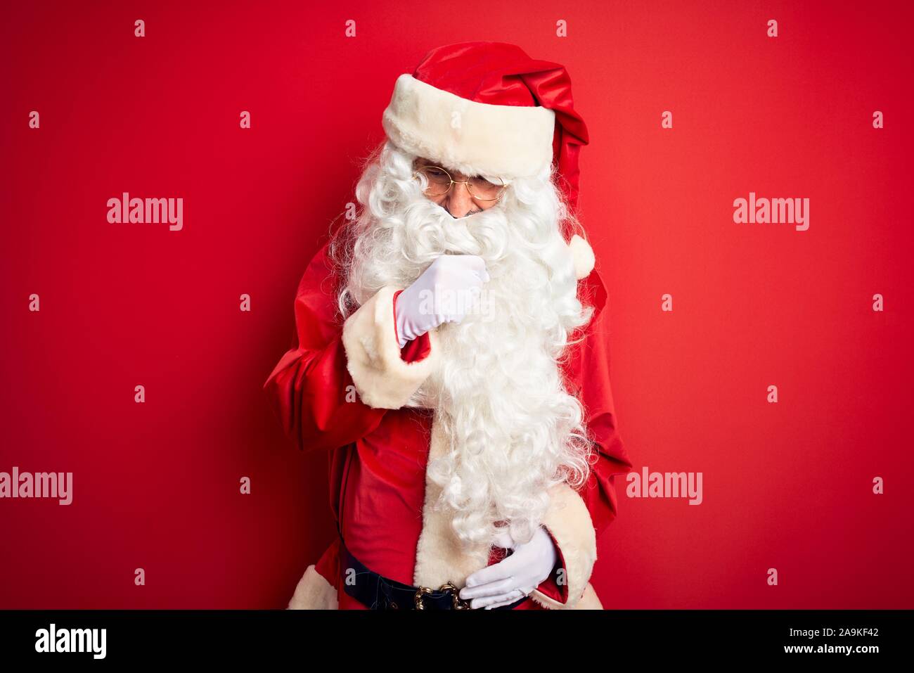 L'âge moyen handsome man wearing Santa costume sur fond rouge isolé ...