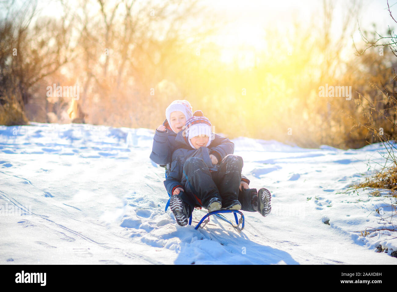 Les enfants jouent dans un parc d'hiver enneigé au coucher du soleil ...