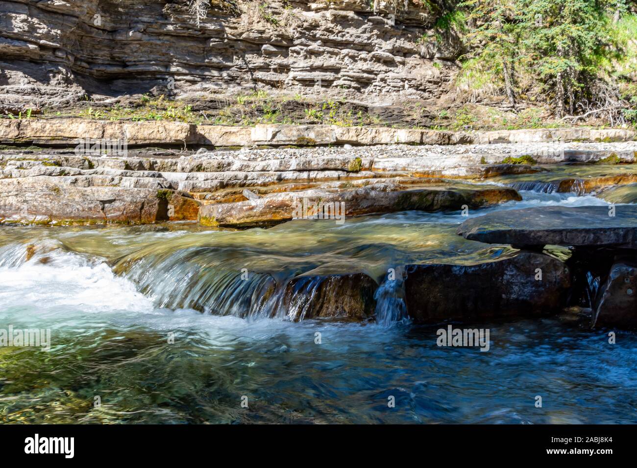 Beau ruisseau de montagne qui coule le long d'une rivière bordée de rochers, avec de beaux ...