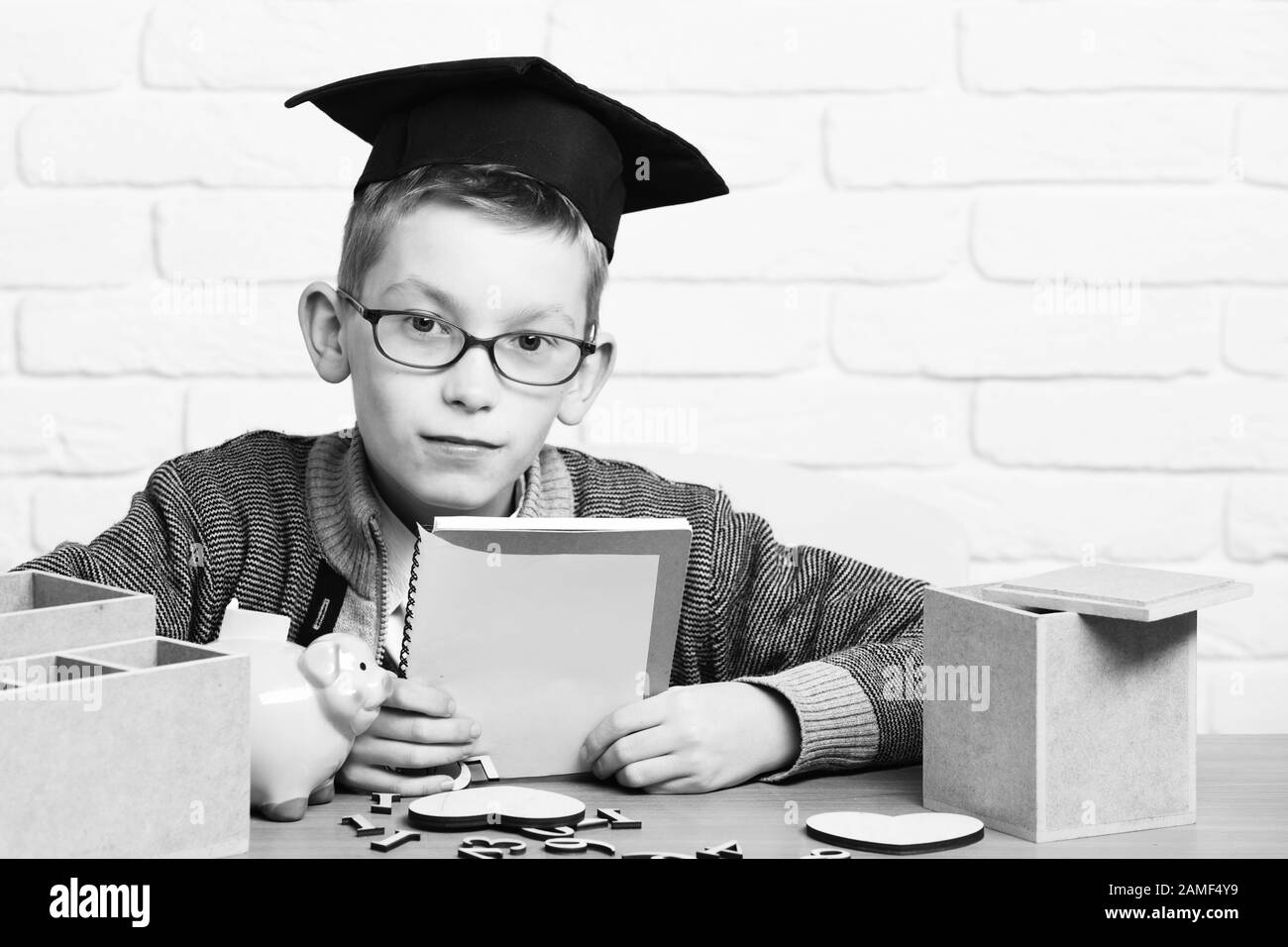 jeune garçon d'élève mignon en chandail gris et verres assis au bureau ...