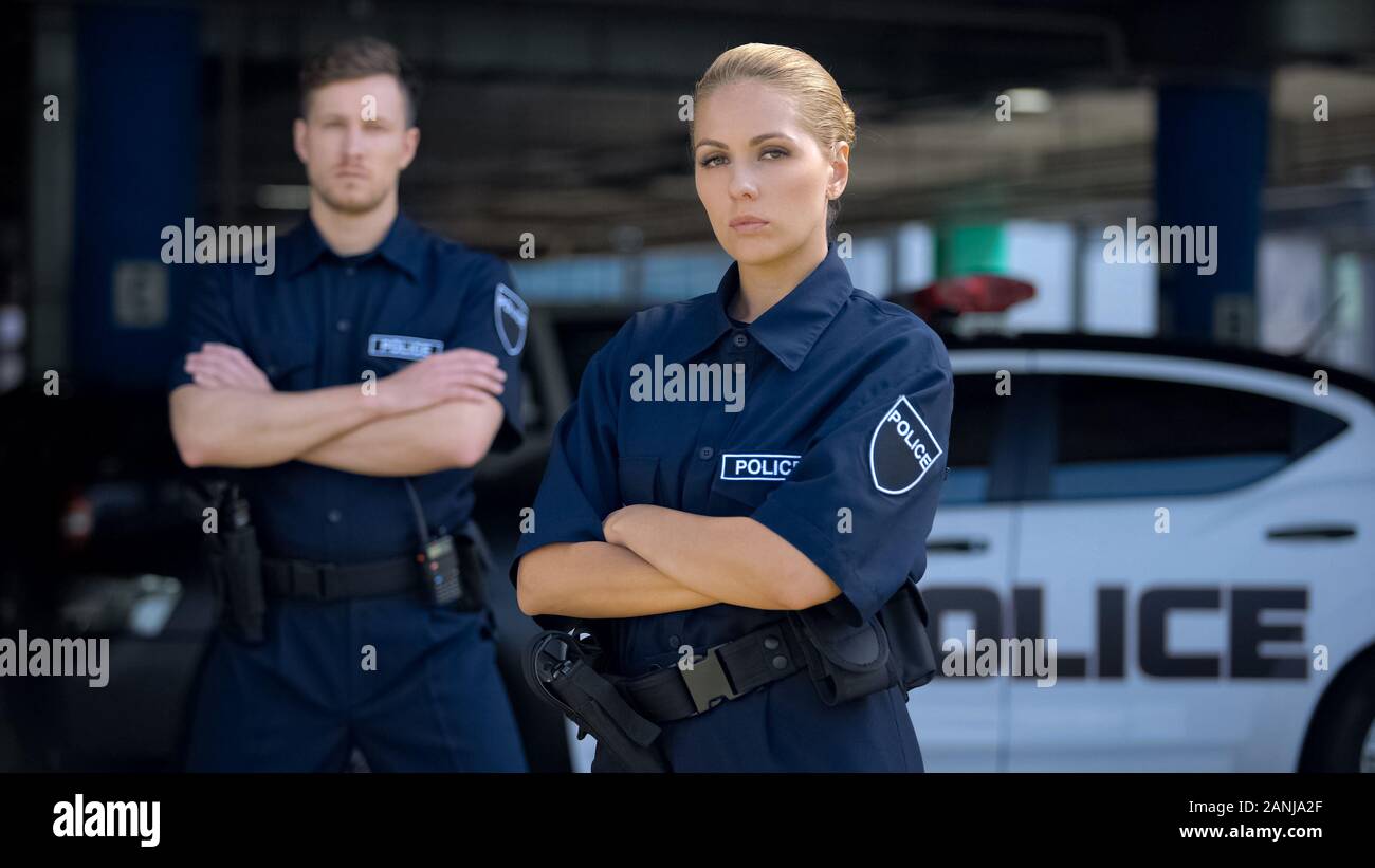 Les agents de police qualifiés posant sur fond de voiture de patrouille ...