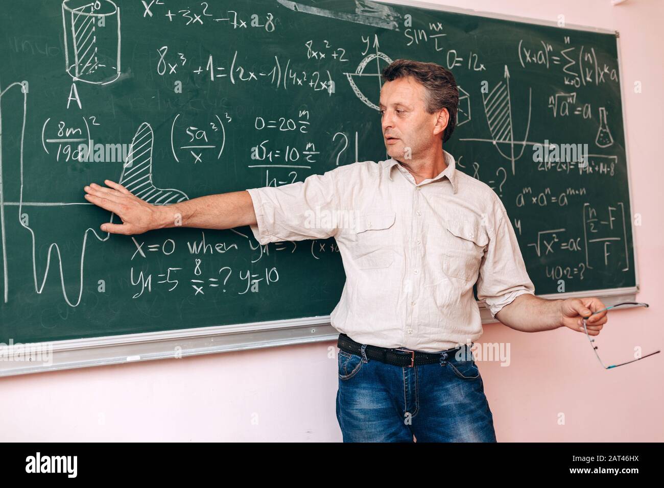 Professeur écrire sur le tableau noir et expliquer une leçon.- image ...