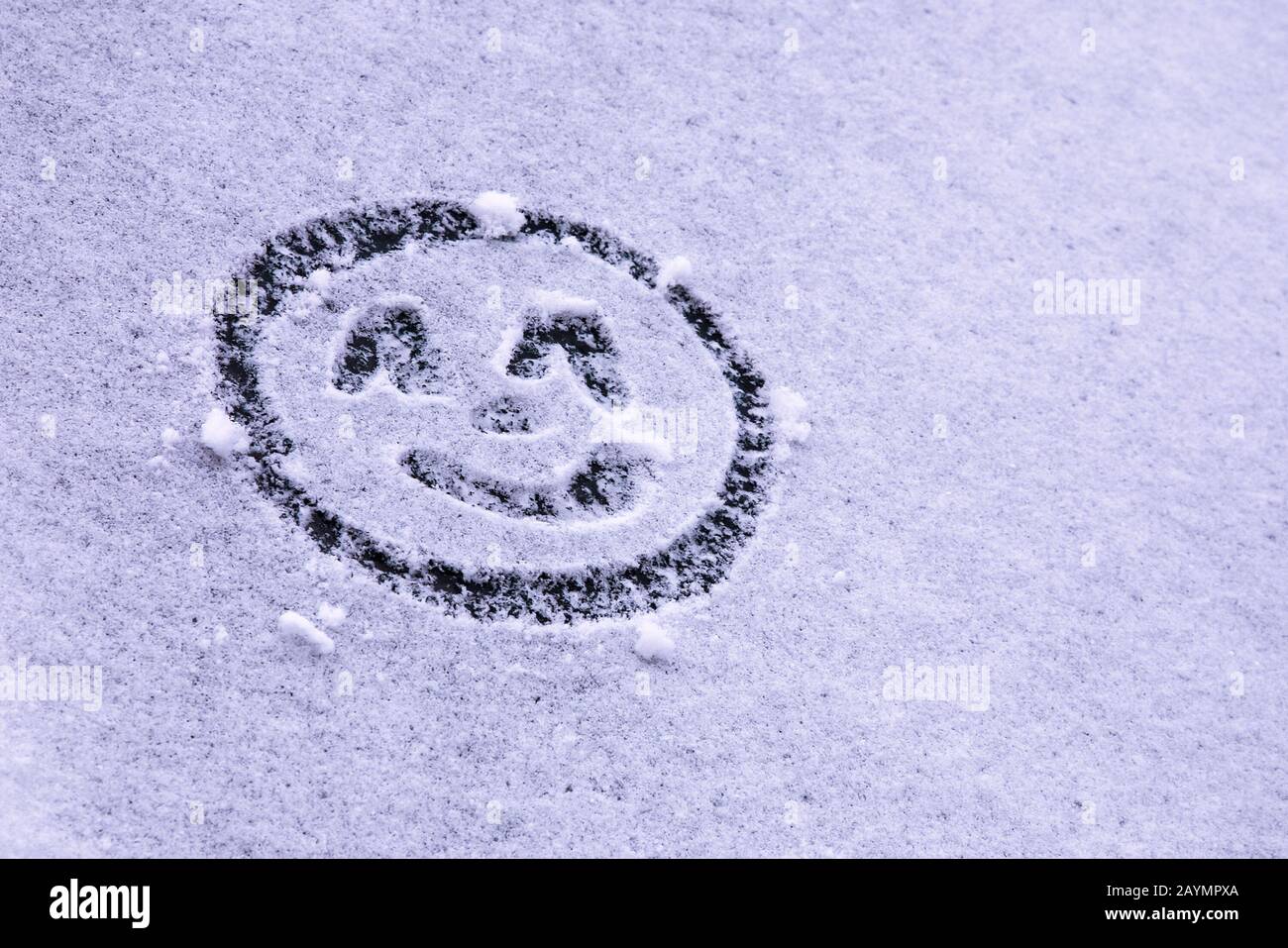 Émoticone souriant et heureux dessiné sur la neige sur le pare-brise ...