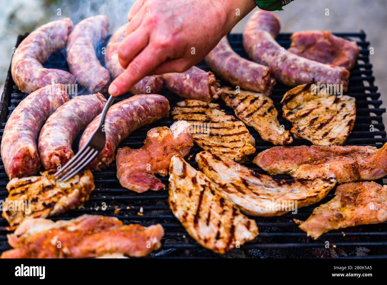 Faire cuire de la viande sur un gril. Saucisses et viande de porc ...