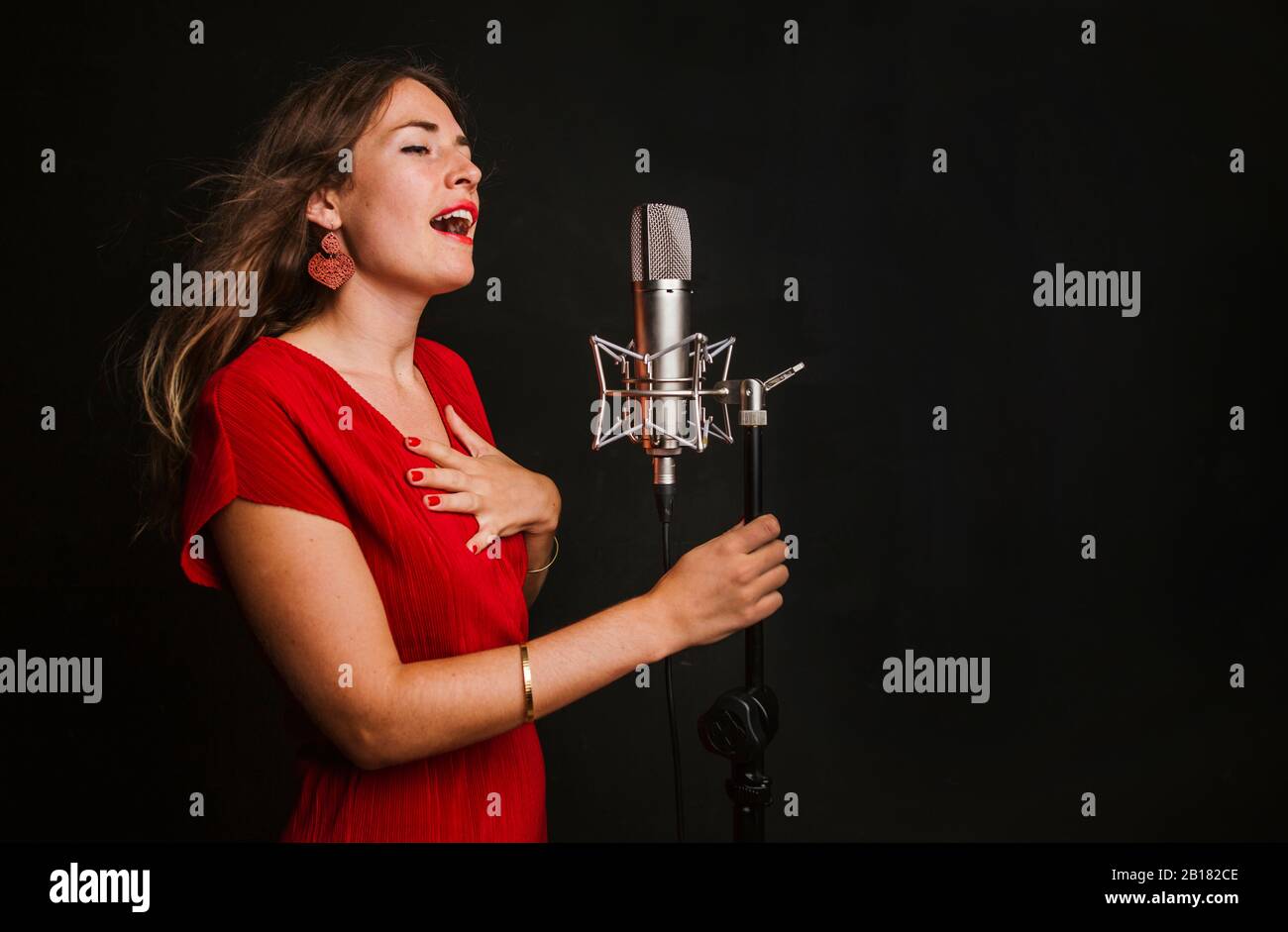 Portrait de la chanteuse féminine avec microphone, portant une robe ...