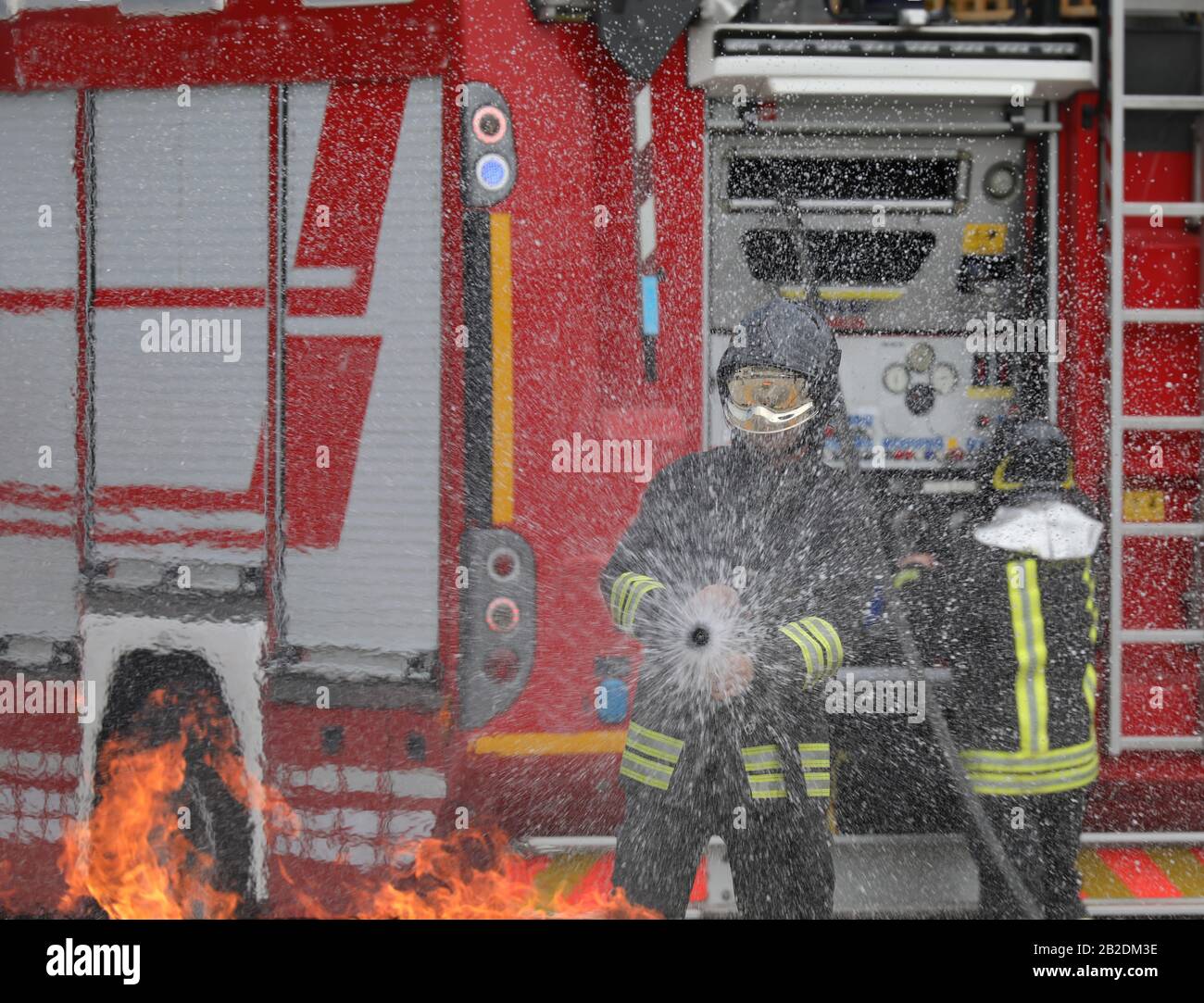 brave pompier avec casque pendant l'extinction d'un incendie tout en ...