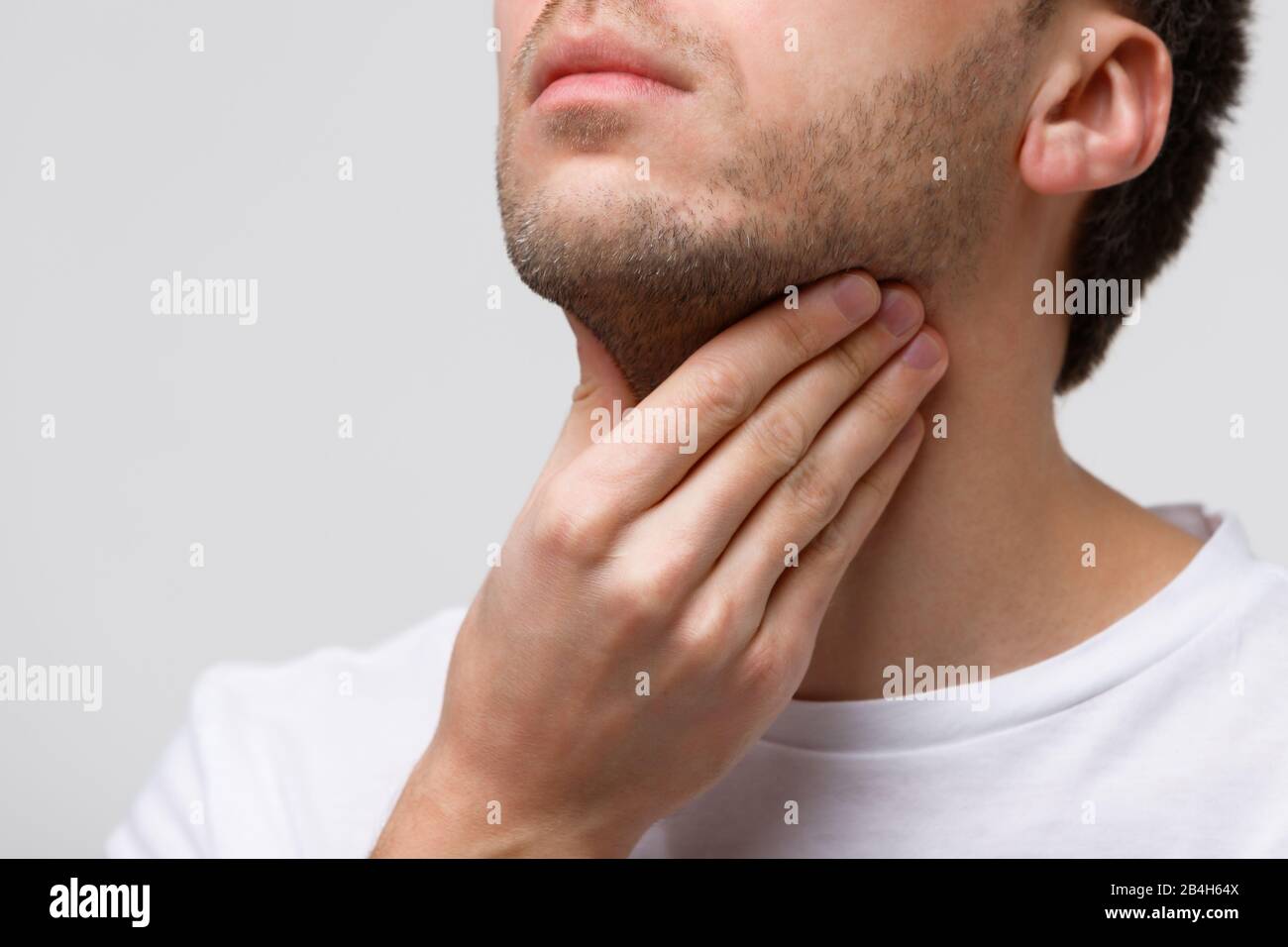 Gros plan sur l'homme malade souffrant de problèmes de gorge, fond gris ...