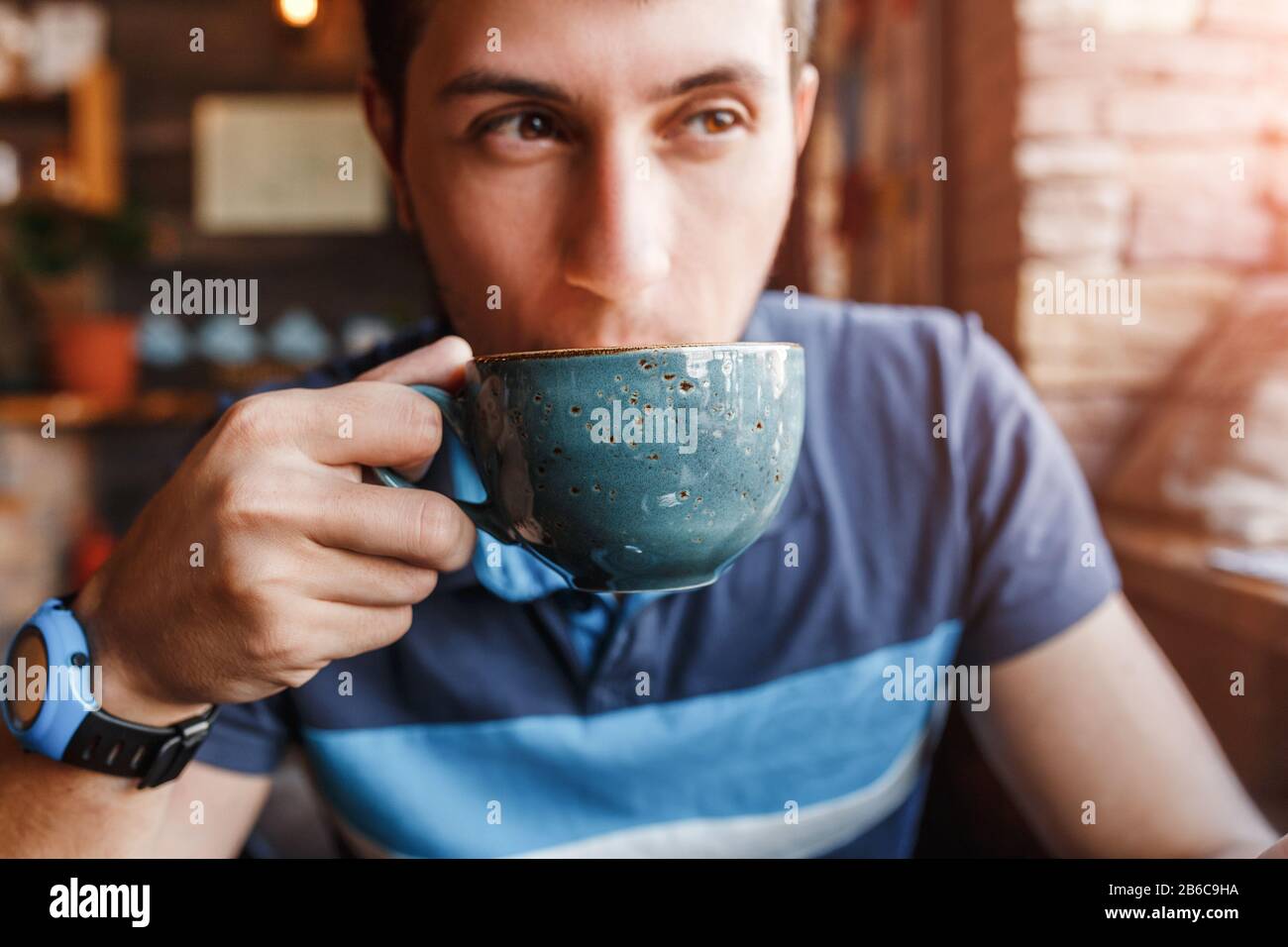 Un jeune homme boit du café aromatique dans un café ou une cafétéria ...