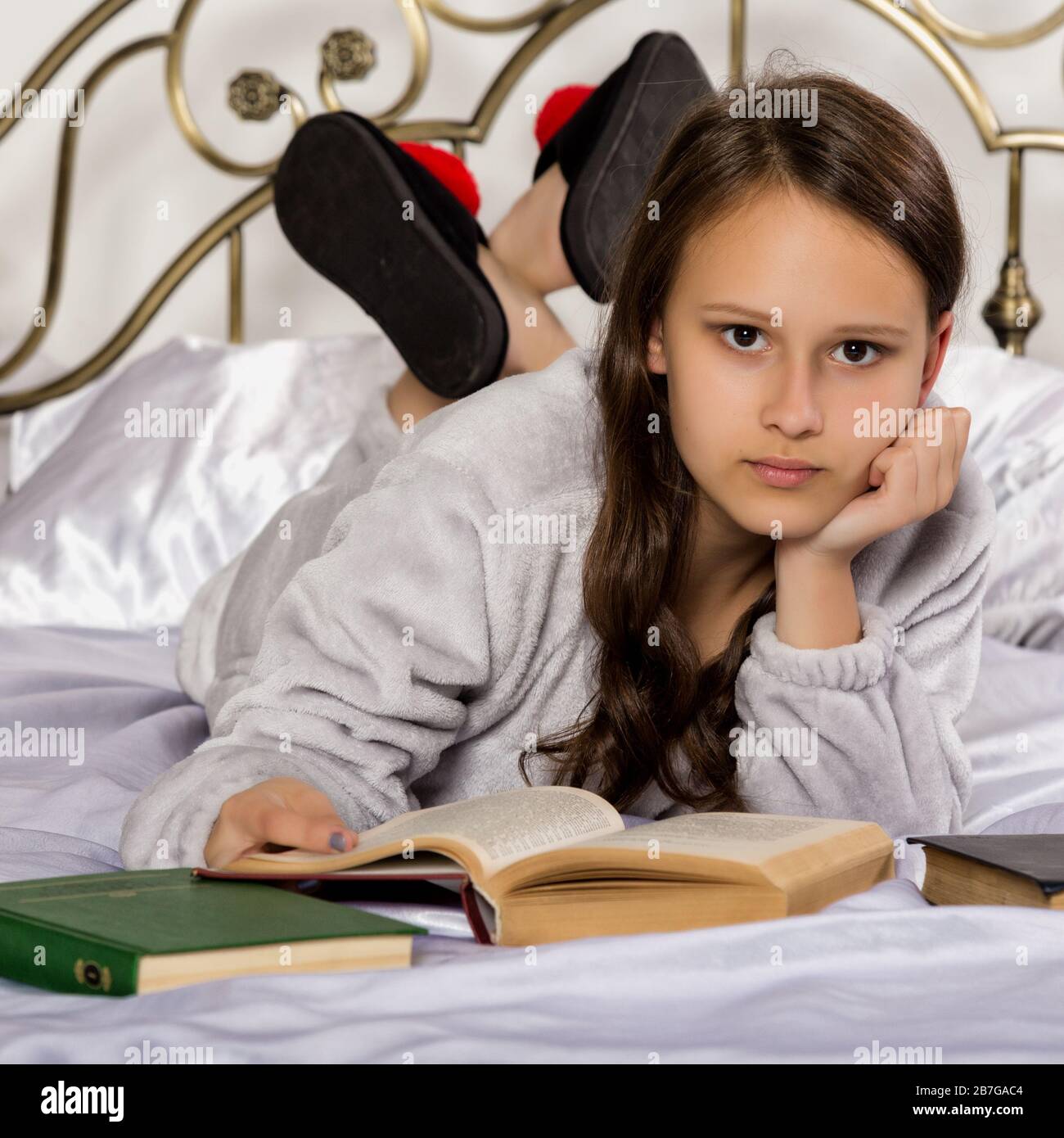 une jeune fille étudiante lit un livre en étant couché sur un lit pour ...