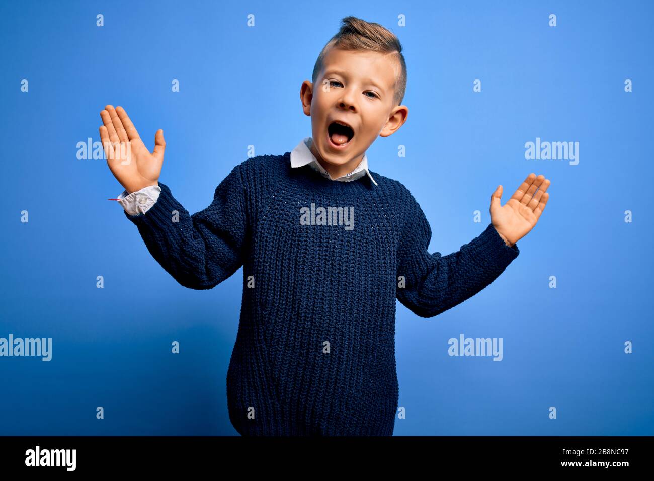 Jeune enfant caucasien avec des yeux bleus portant un pull d'hiver sur ...