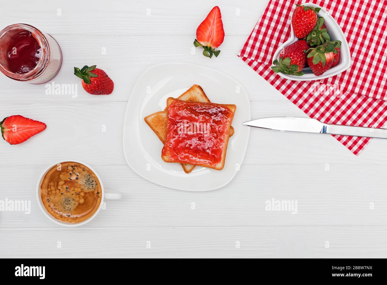 Toasts avec confiture de fraises, fraises et café sur la table blanche ...