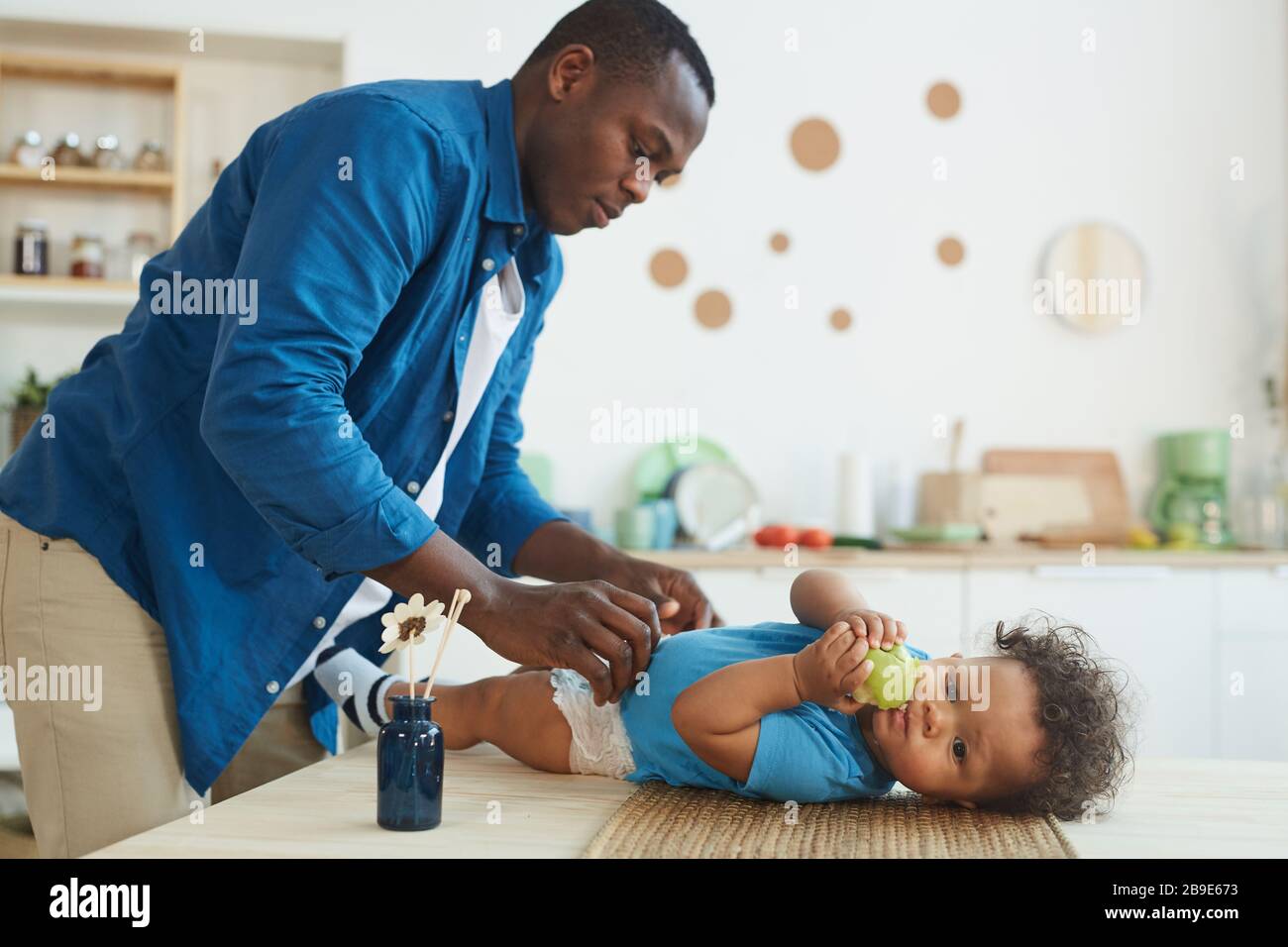 Portrait latéral du père afro-américain changeant de couches à la ...