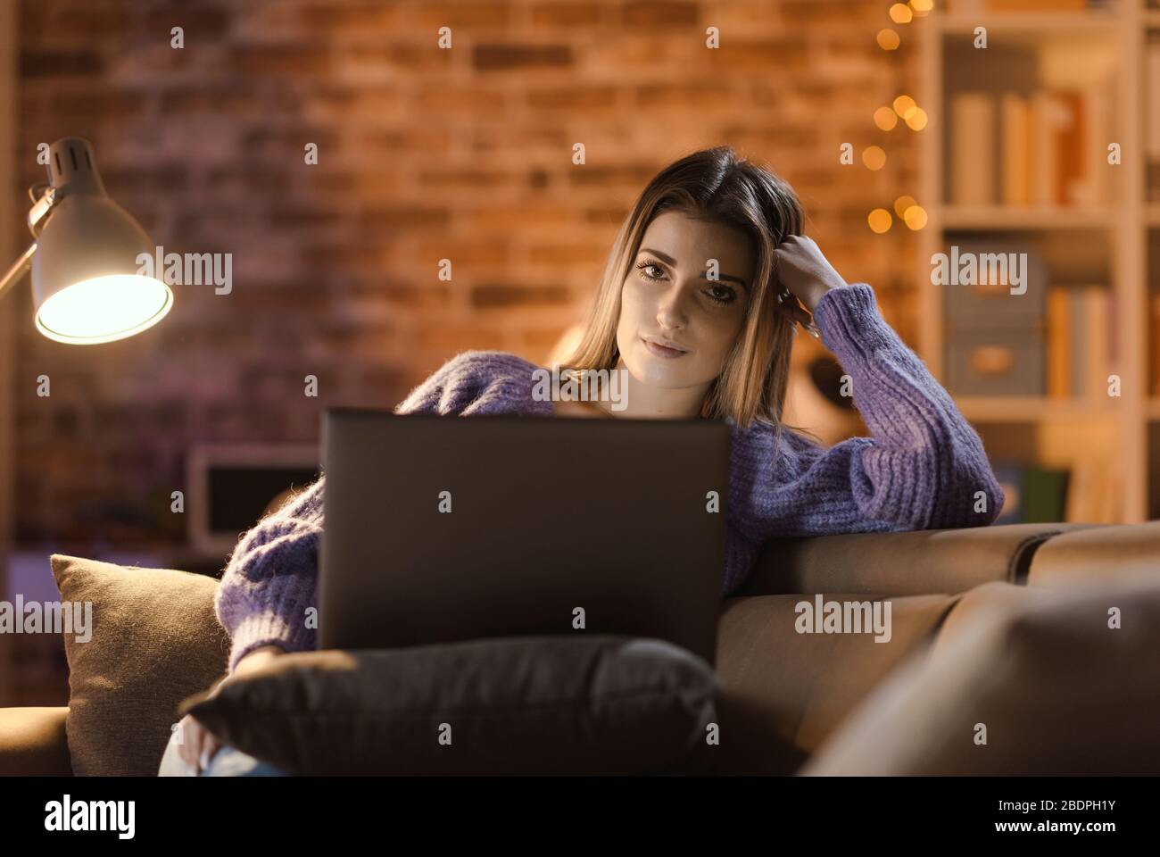 Jeune femme attrayante se reposant à la maison sur le canapé et regarder des films en ligne sur ...