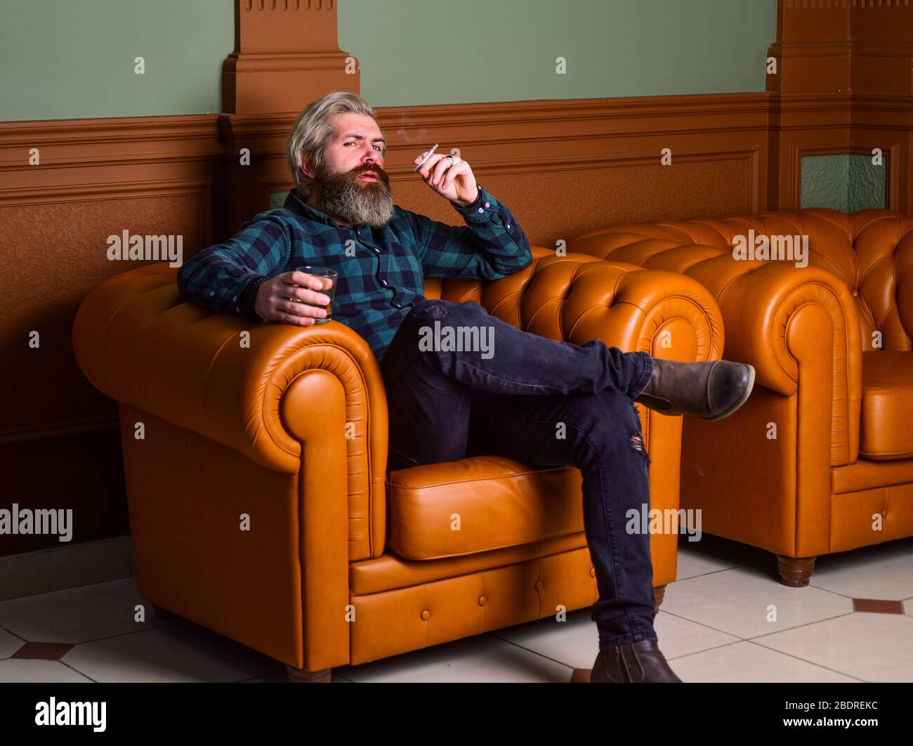 homme brutal buvant du whisky et fume de cigarette. homme barbu assis ...