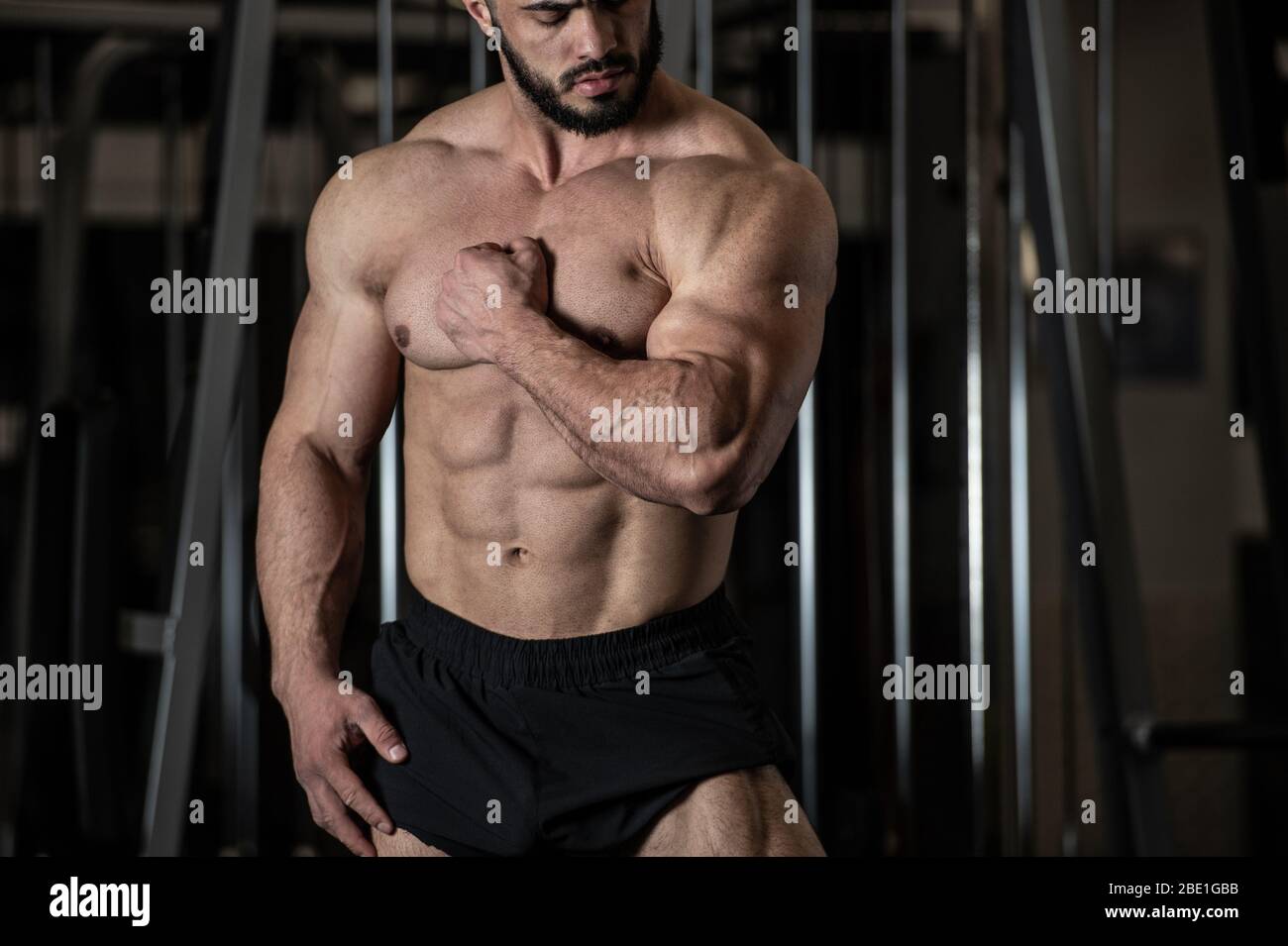 bel homme barbu dans des malles de sport montrant le muscle fort de son ...