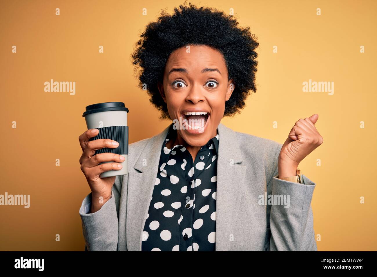 Jeune afro-américaine femme d'affaires afro-américaine avec cheveux bouclés boire une tasse de ...