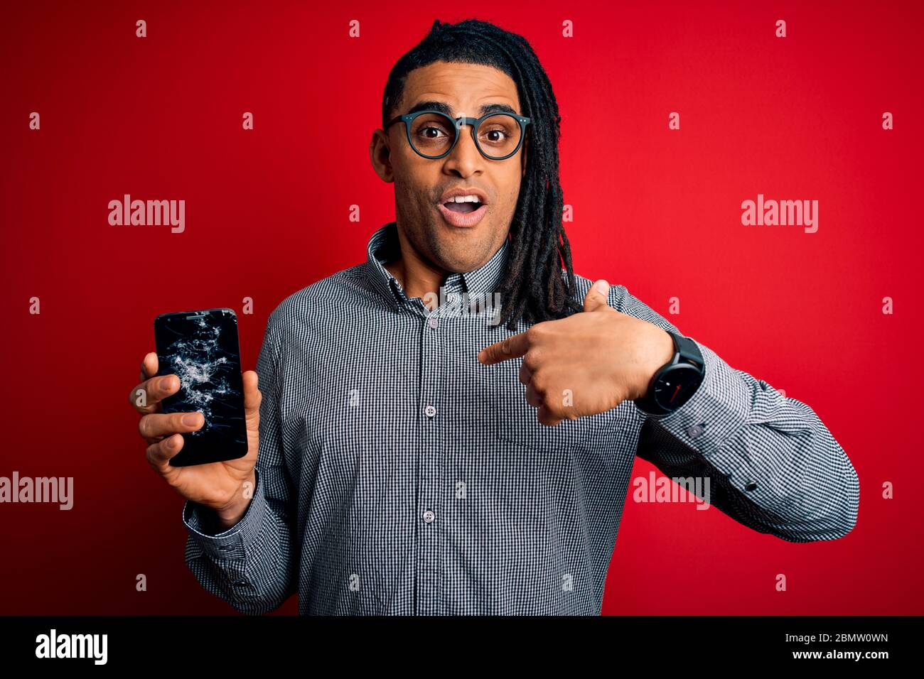 Jeune afro-américain africain tenant un smartphone cassé montrant un ...