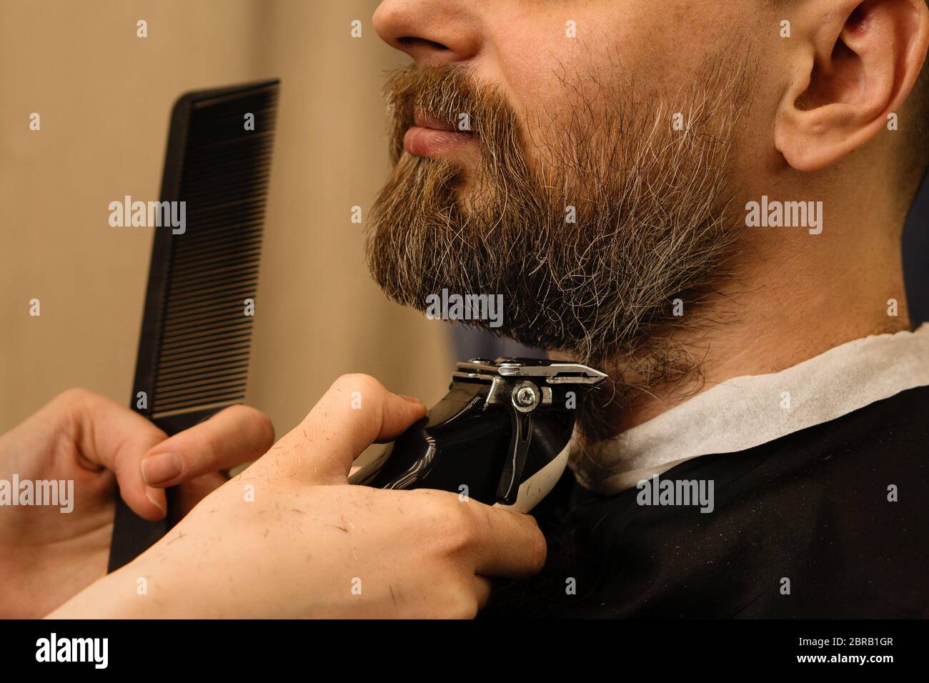 Barbier tailler la barbe d'un client masculin avec un rasoir électrique ...