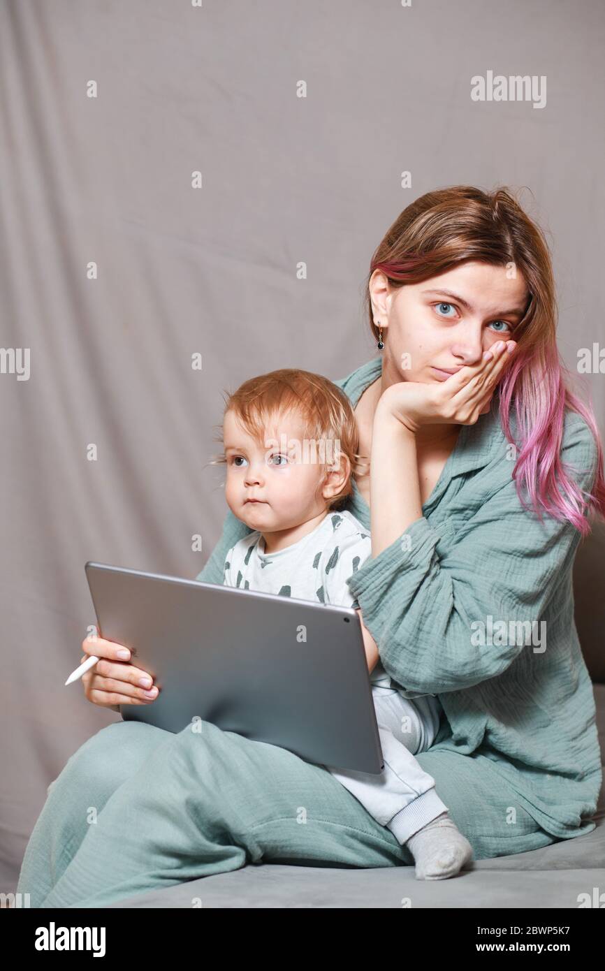 Une Jeune Femme Travaille à La Maison Avec Une Tablette Avec Un Enfant