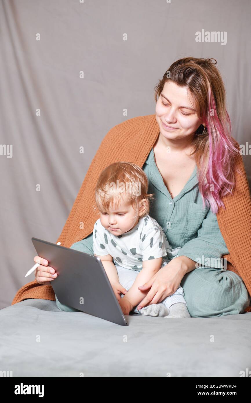 Une Jeune Femme Travaille à La Maison Avec Une Tablette Avec Un Enfant