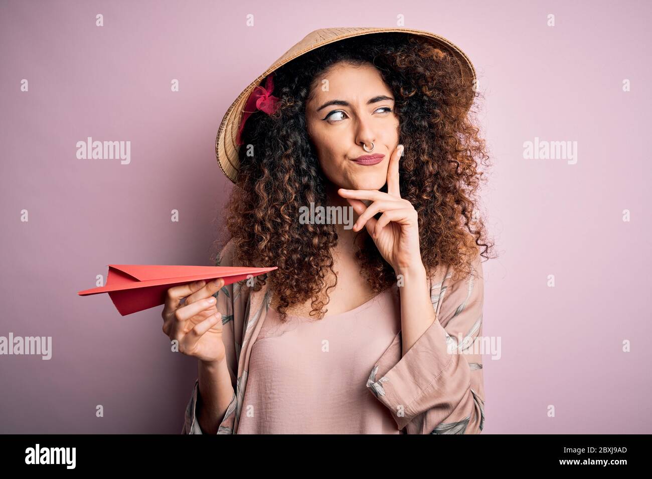 Jeune belle femme avec des cheveux bouclés et piercing portant un ...