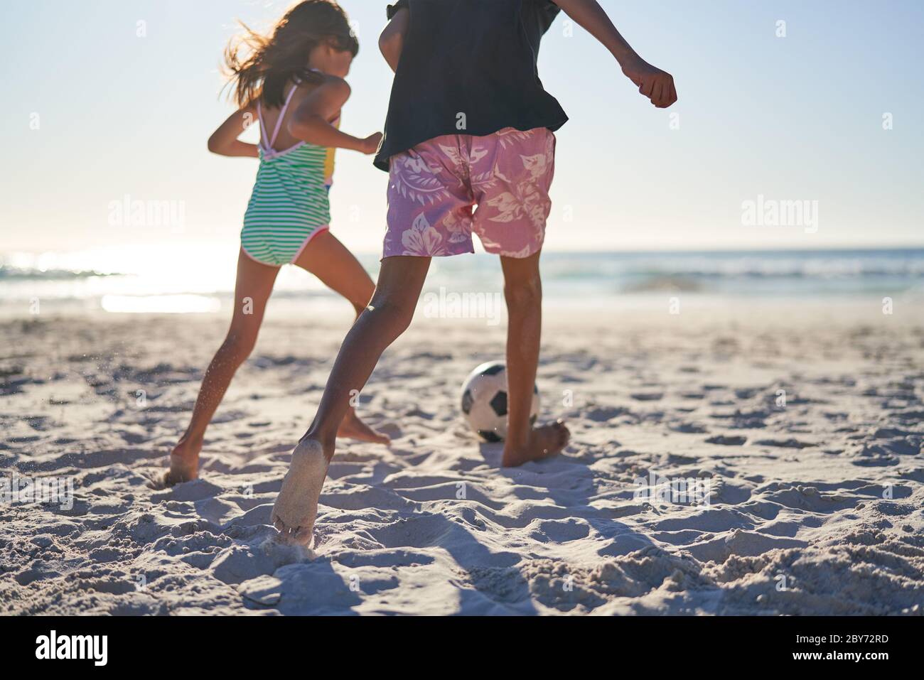 Frère Et Sœur Jouant Au Football Sur Une Plage Ensoleillée Photo Stock