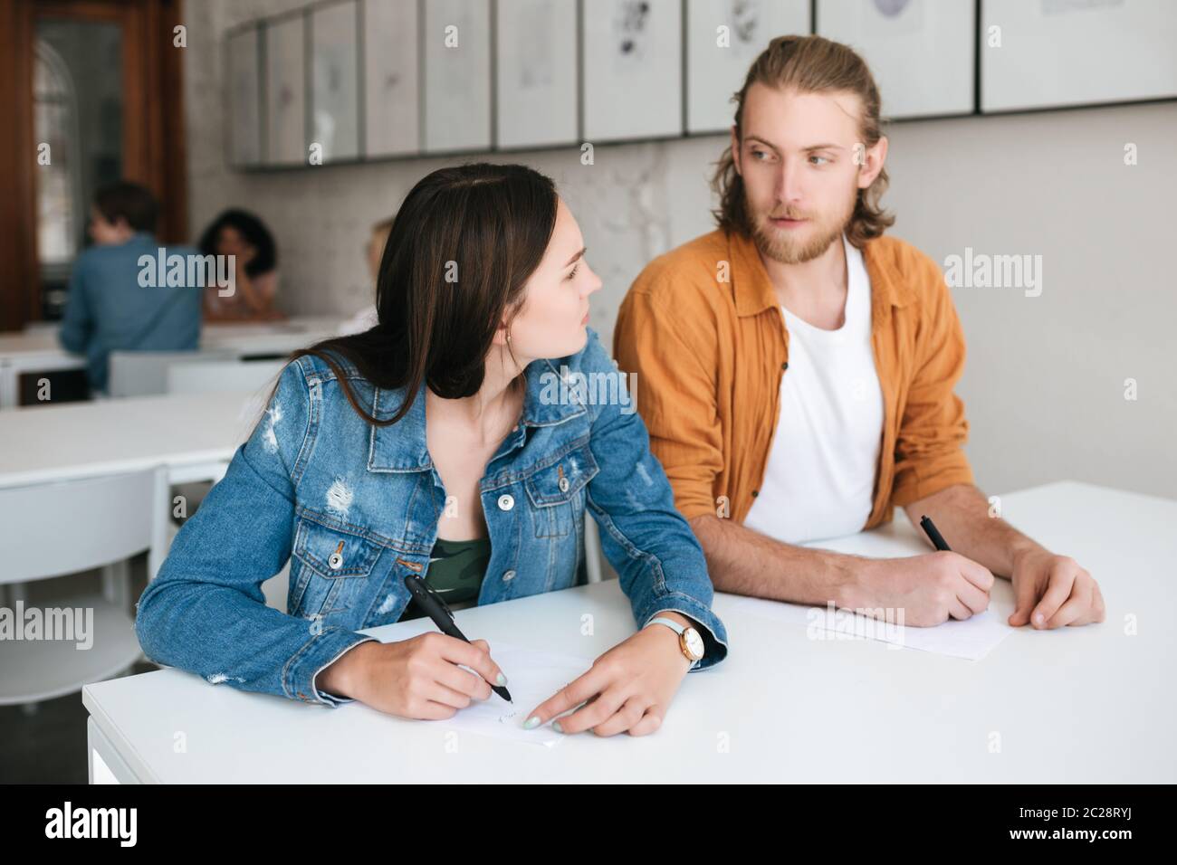 Portrait de deux élèves assis au bureau en classe et regardant de ...