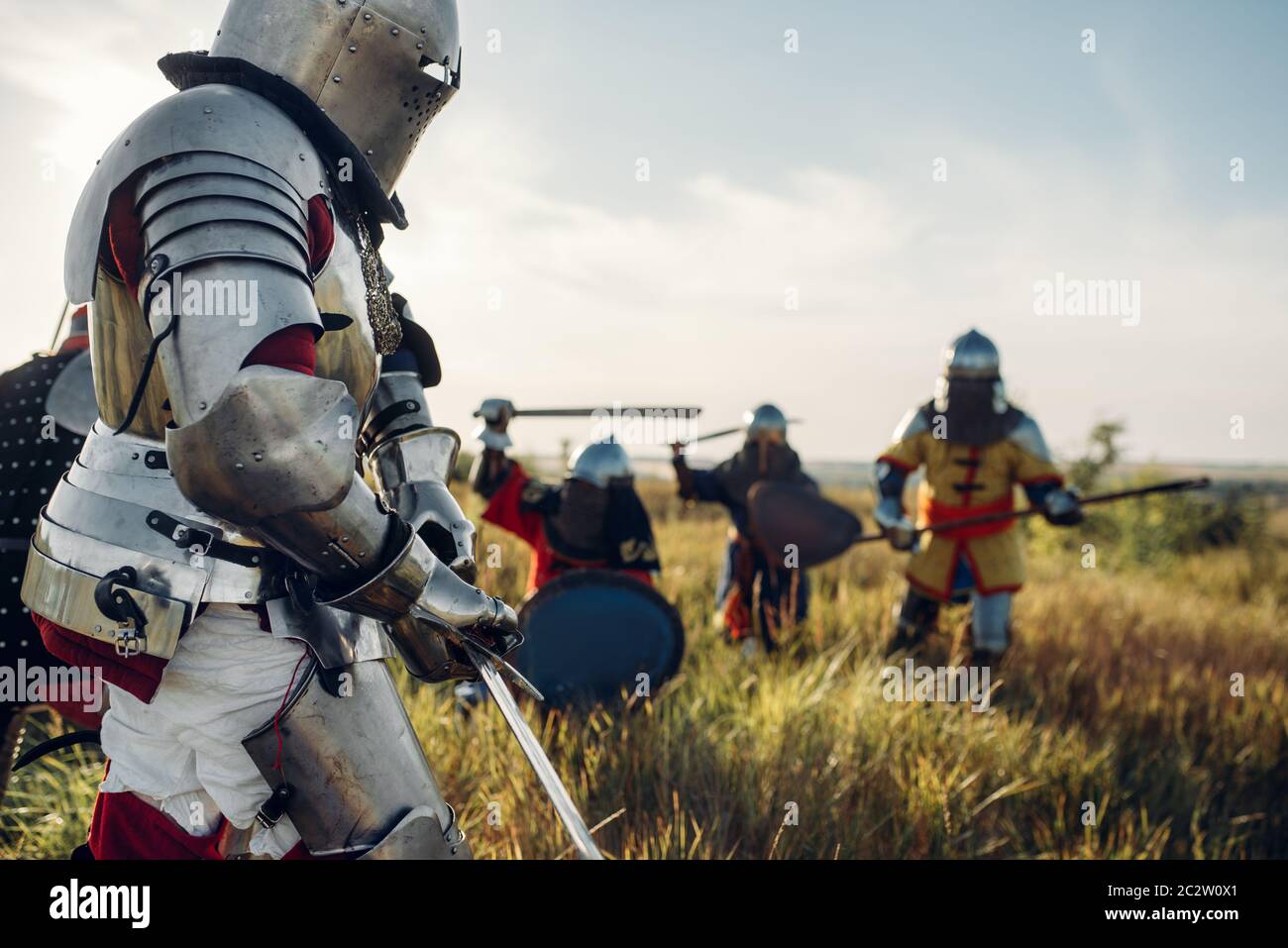 Les chevaliers médiévaux en armure et casques se battent avec l'épée et ...