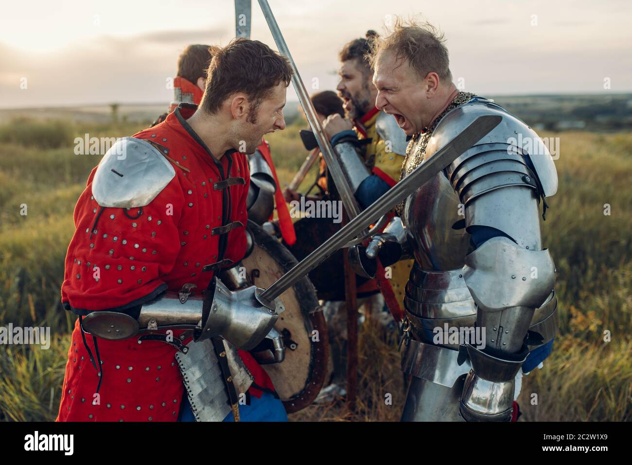 Les chevaliers médiévaux en armure et casques se battent avec l'épée et ...