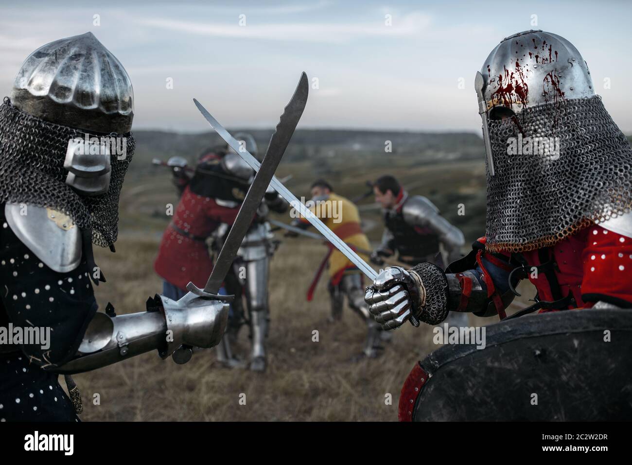 Les chevaliers médiévaux en armure et casques se battent avec des épées ...