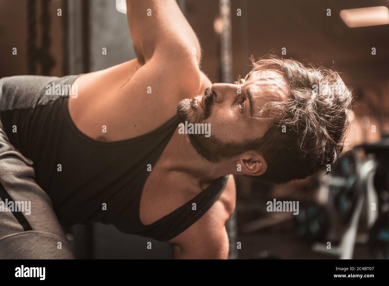 Un homme sportif barbu dans la salle de gym fait des exercices de yoga ...