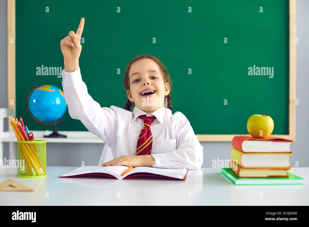 Retour à l'école. Concept à l'école. Une jeune fille gaie a soulevé le doigt tout en étant ...