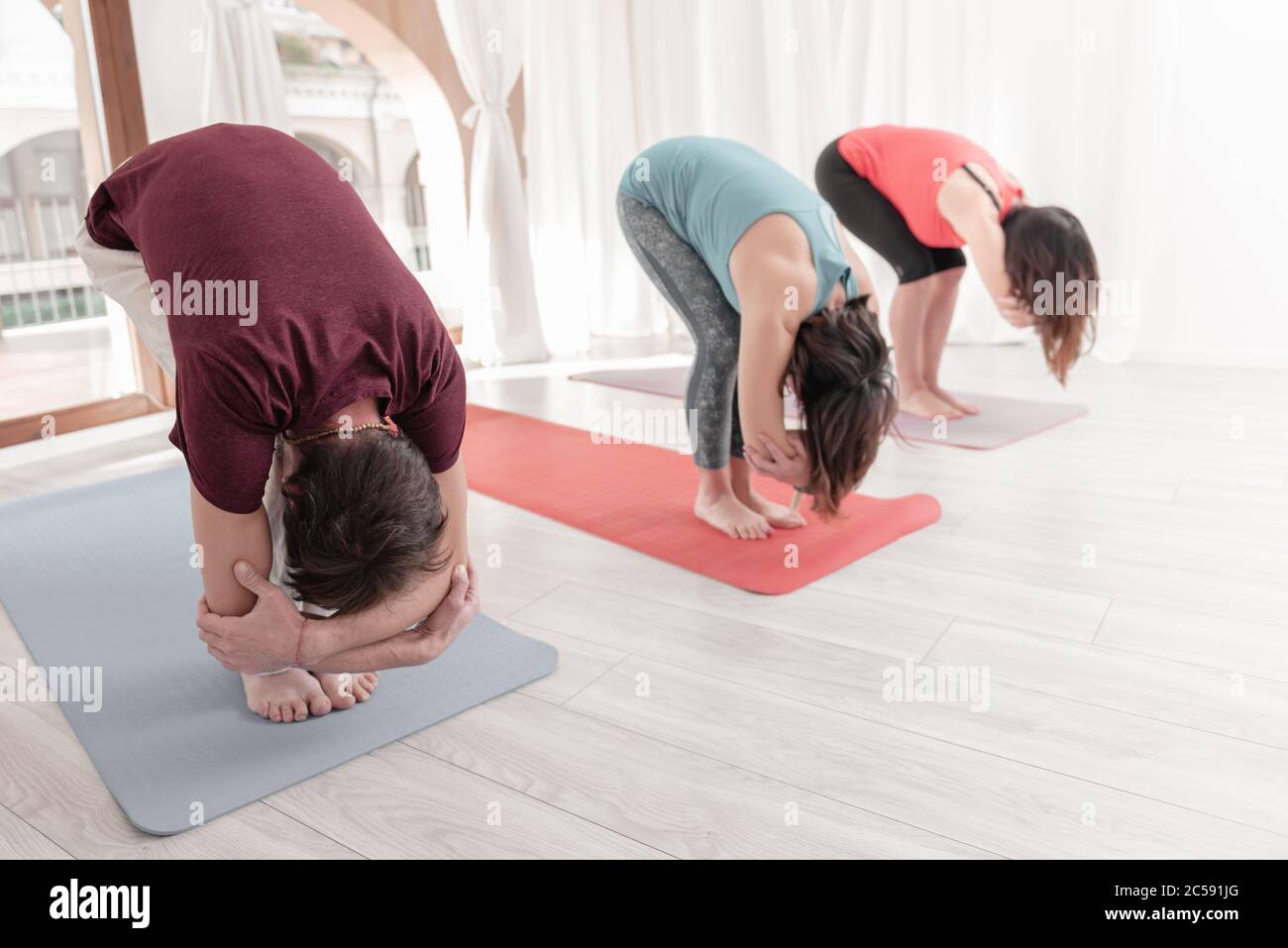 Groupe de personnes pratiquant le yoga. Position Uttanasana avec pince ...